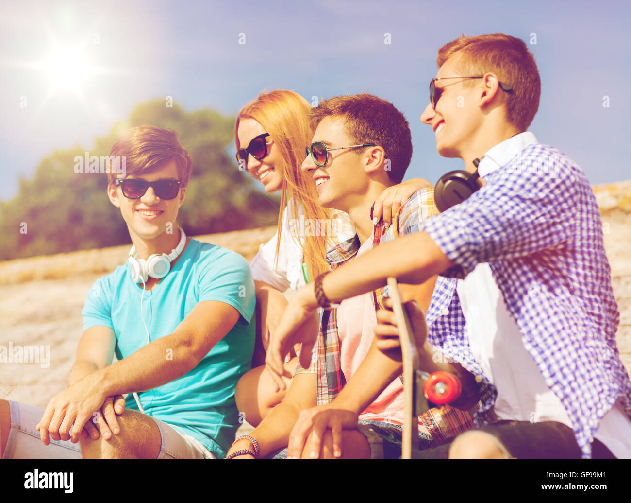 group of smiling friends sitting on city street Stock Photo - Alamy