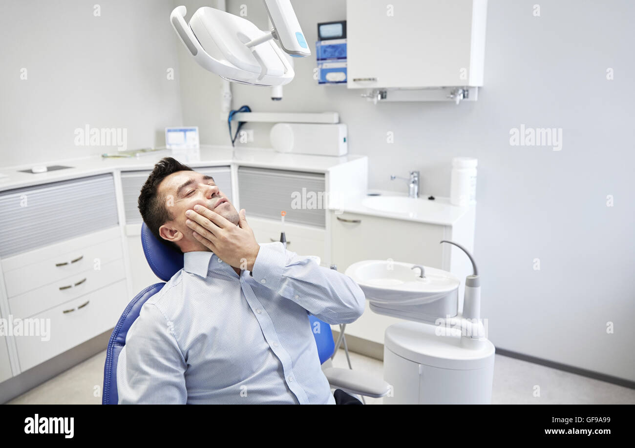 man having toothache and sitting on dental chair Stock Photo - Alamy