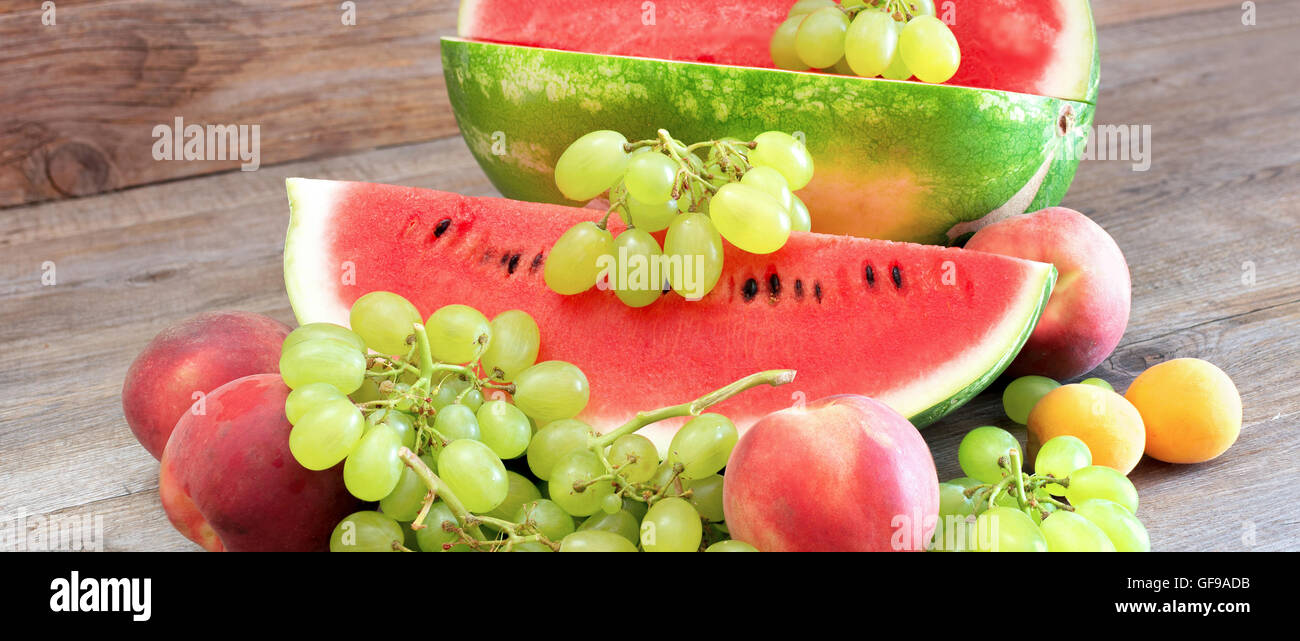 red and sweet summer fruits on wooden table which watermelon, grapes ...