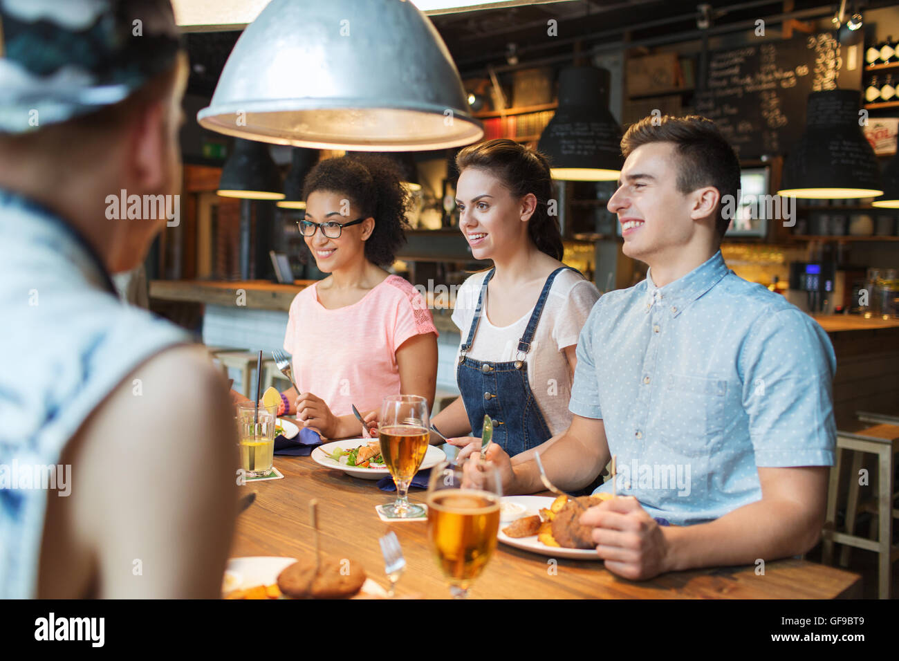 happy friends eating and drinking at bar or pub Stock Photo - Alamy