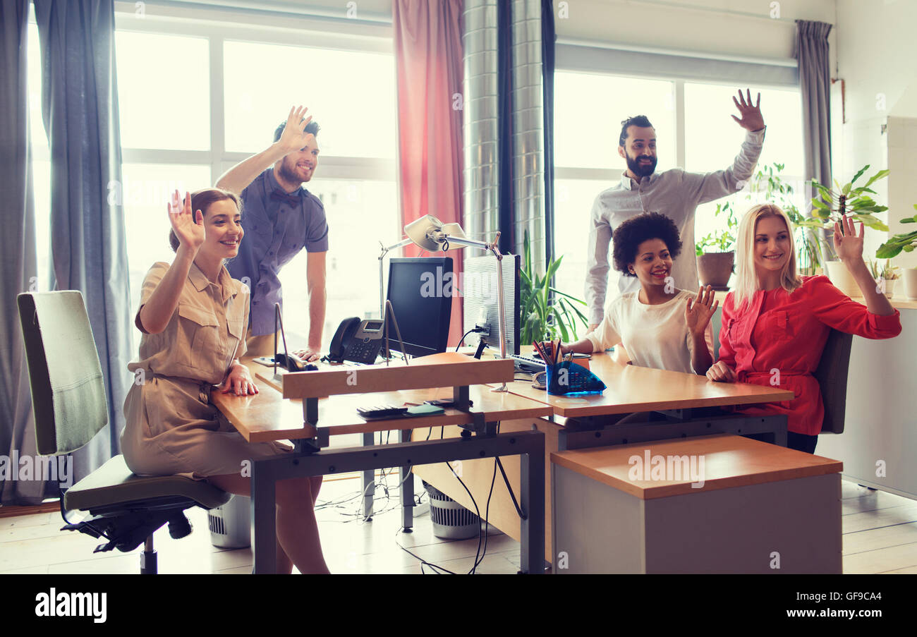 happy creative team waving hands in office Stock Photo - Alamy