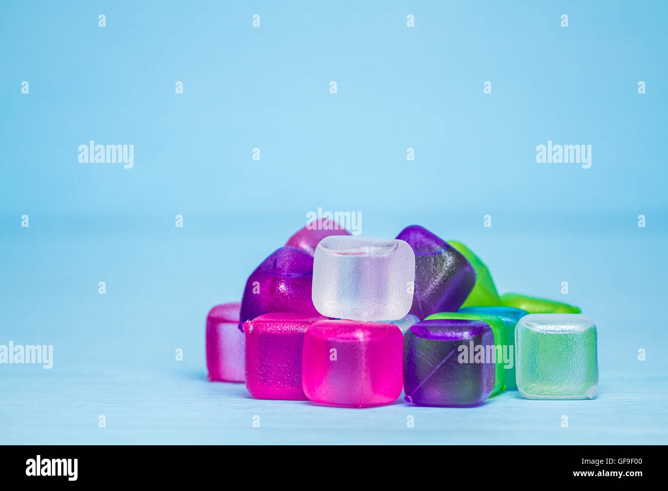 Colorful small plastic ice cubes on blue background Stock Photo - Alamy