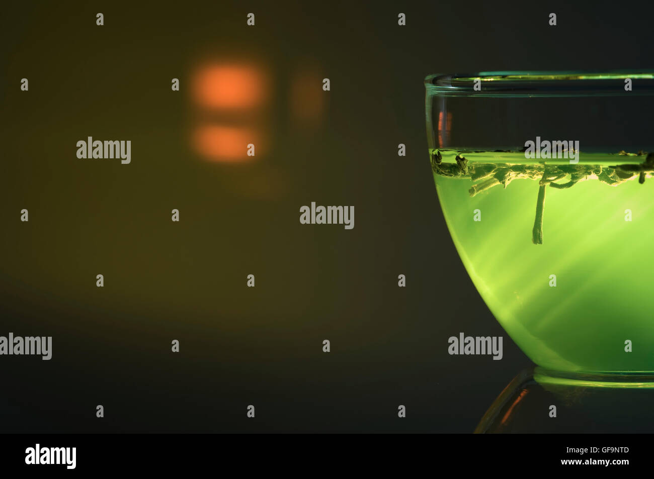 Cut to close up a glass cup against Green-lit background with bright ...