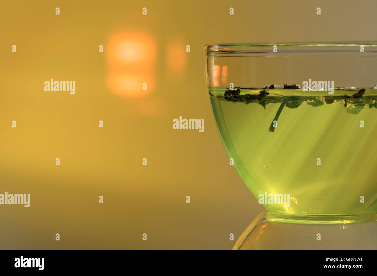 Cut to close up a glass cup against Green-lit background with bright ...