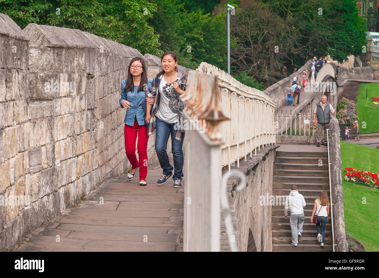 A pair of young Chinese tourists walk along the medieval stone wall ...