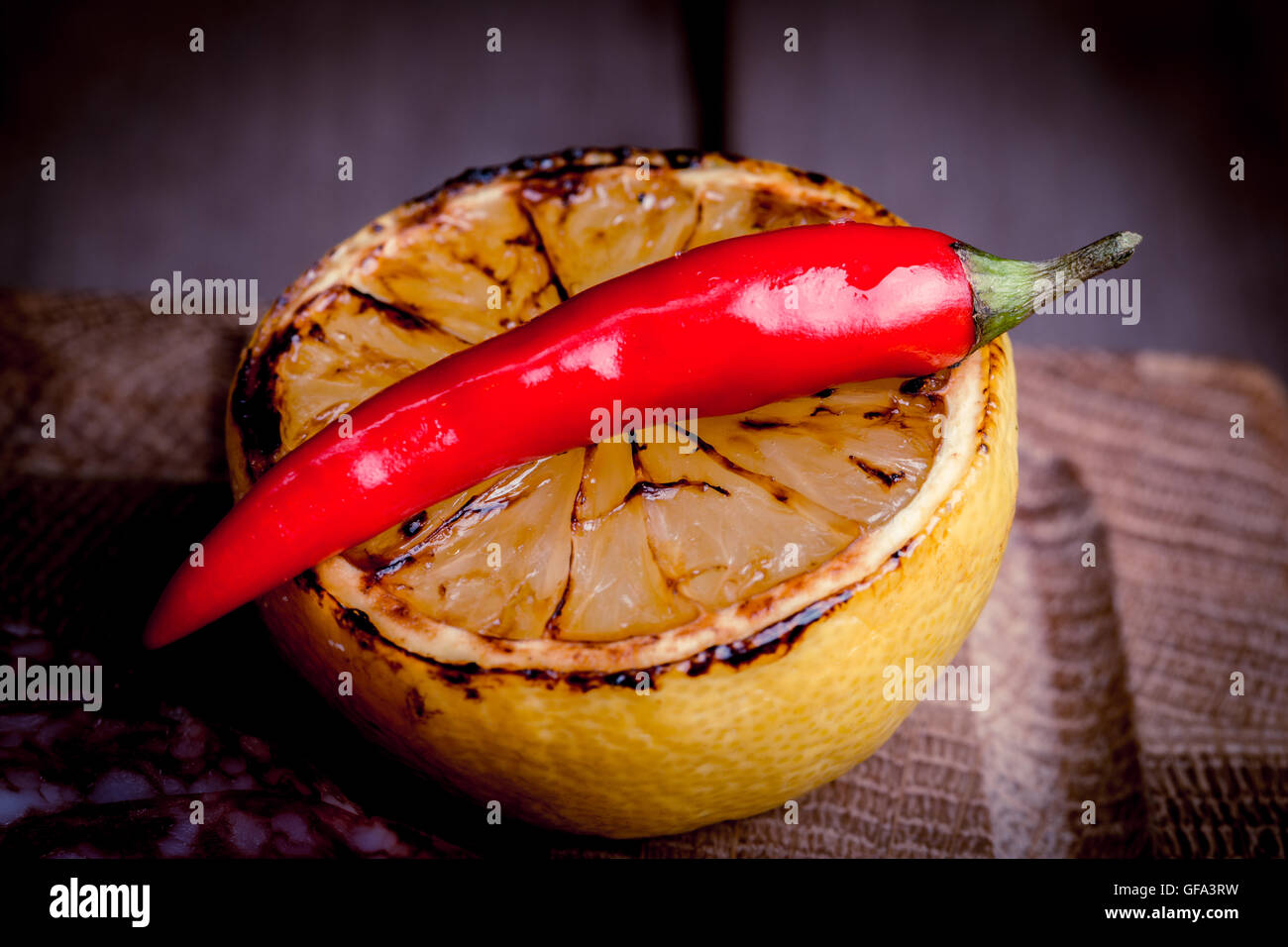 A red chilli on top of a chargrilled lemon, used as a garnish for a ...