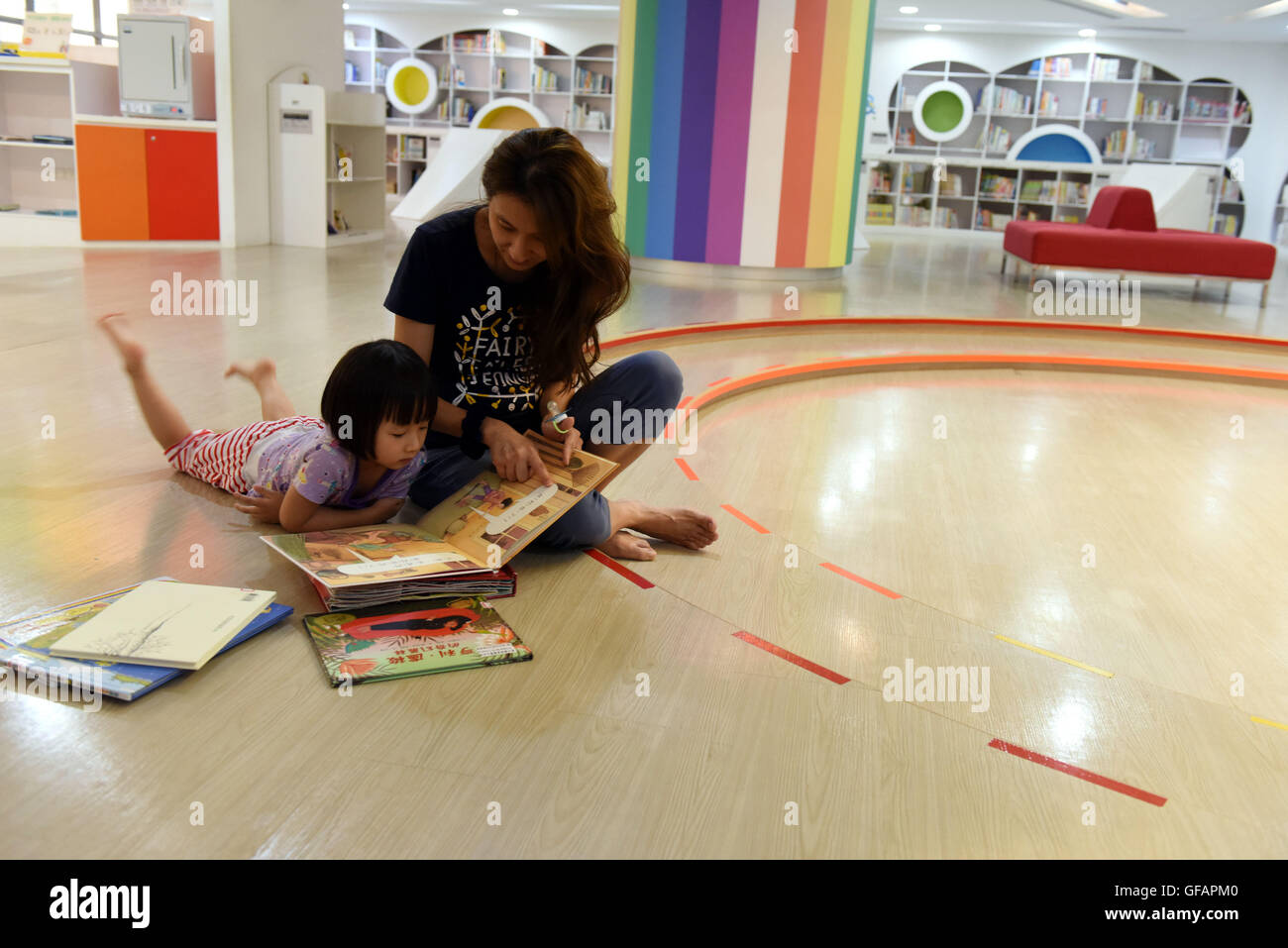 New Taipei. 30th July, 2016. A woman and her daughter read at the young ...