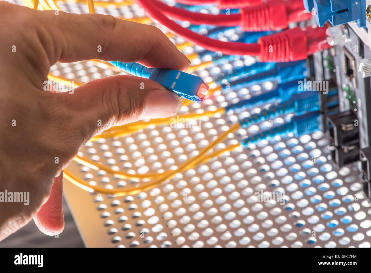 man working in network server room with fiber optic hub for digital ...