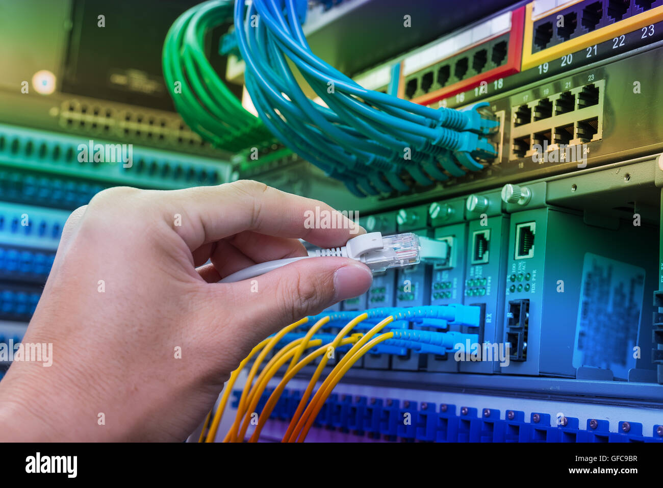 man working in network server room with fiber optic hub for digital ...