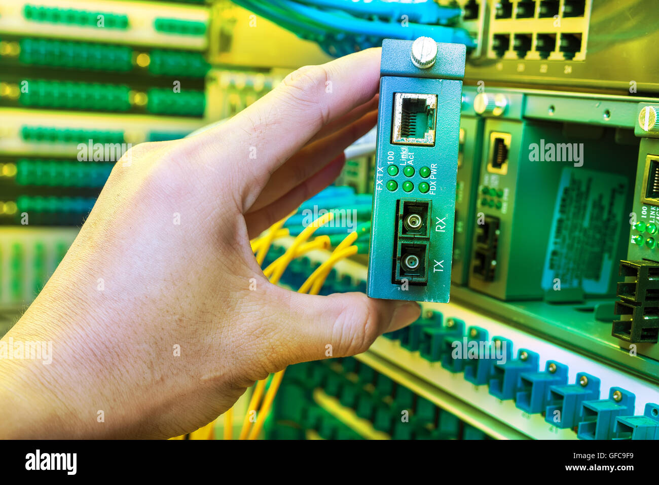 man working in network server room with fiber optic hub for digital ...