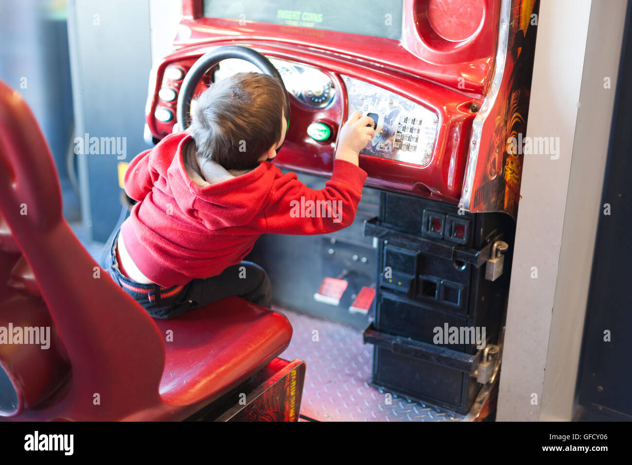 Rear view of a boy playing driving game at video game arcadecolor image ...