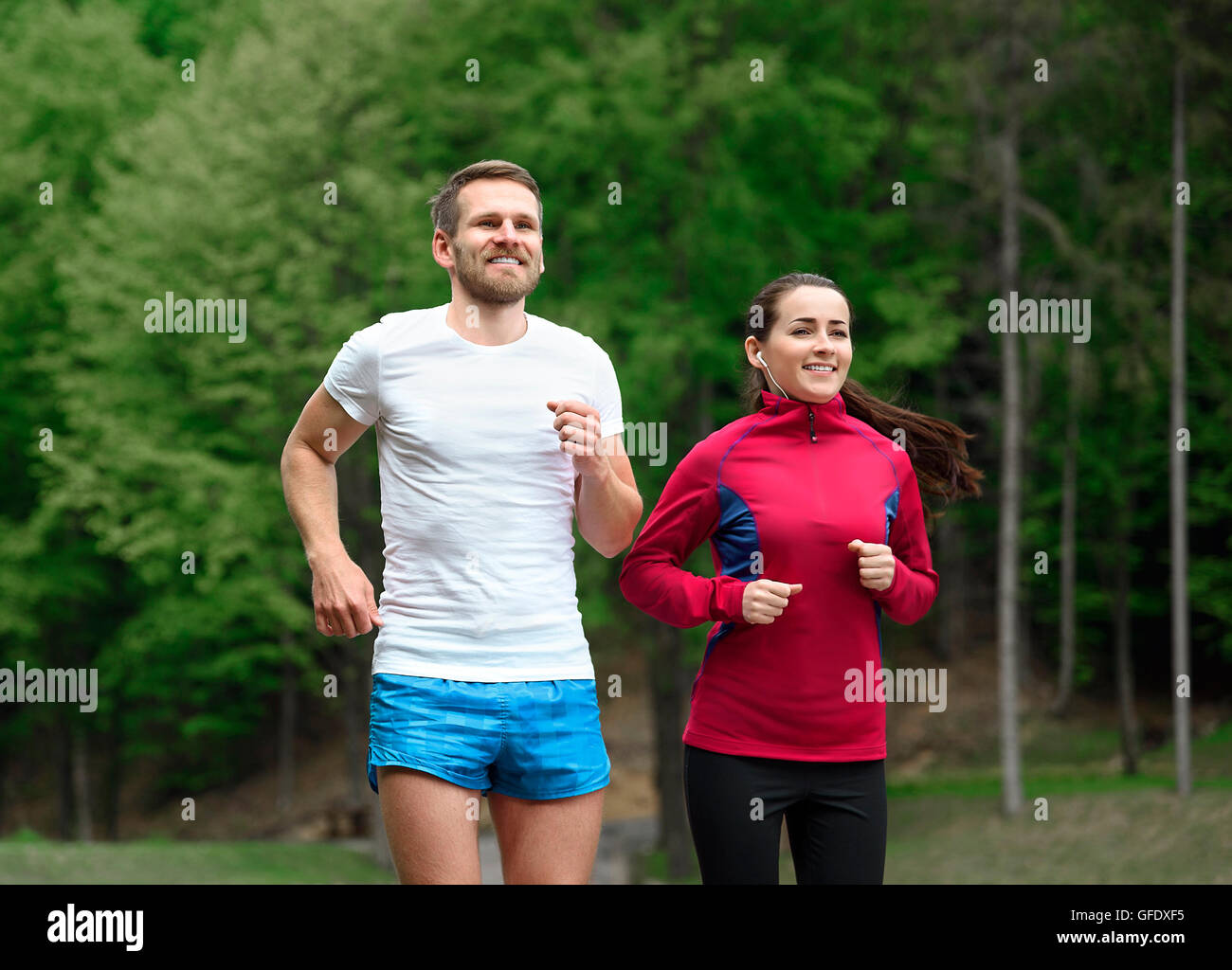 Attractive caucasian couple friends running in park Stock Photo - Alamy