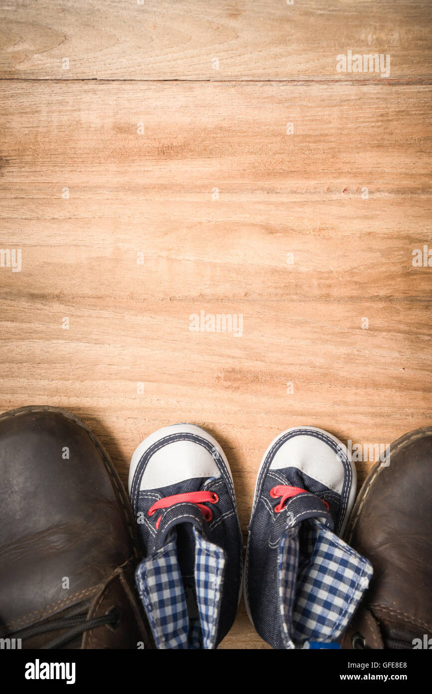 Daddy's boots and baby's sneakers, on wood background, fathers day ...
