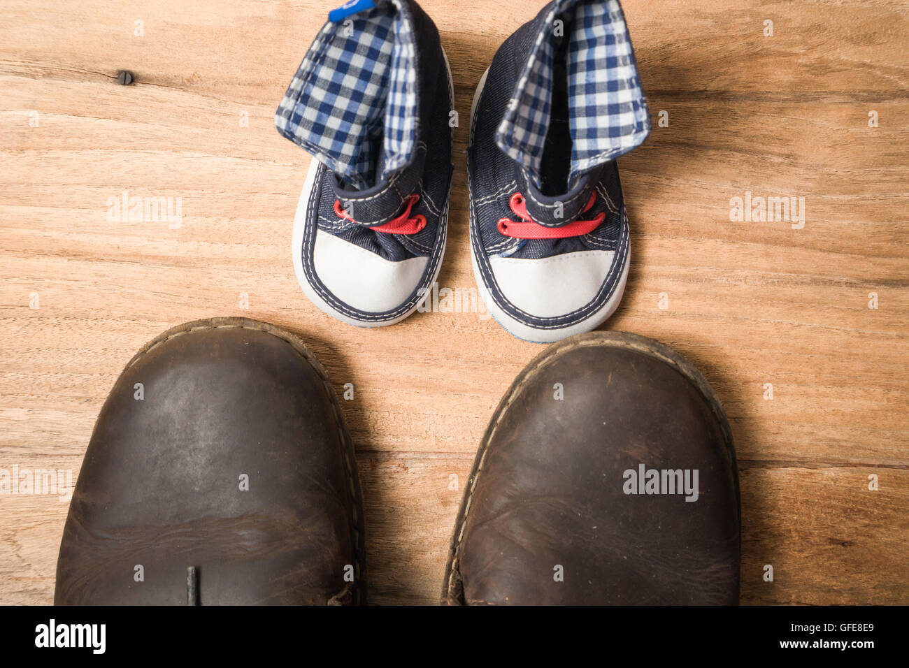 Daddy's boots and baby's sneakers, on wood background, fathers day ...