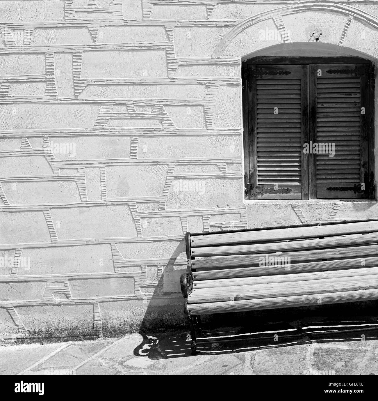 and stone pavement in the greece island of paros old bench near a brick ...