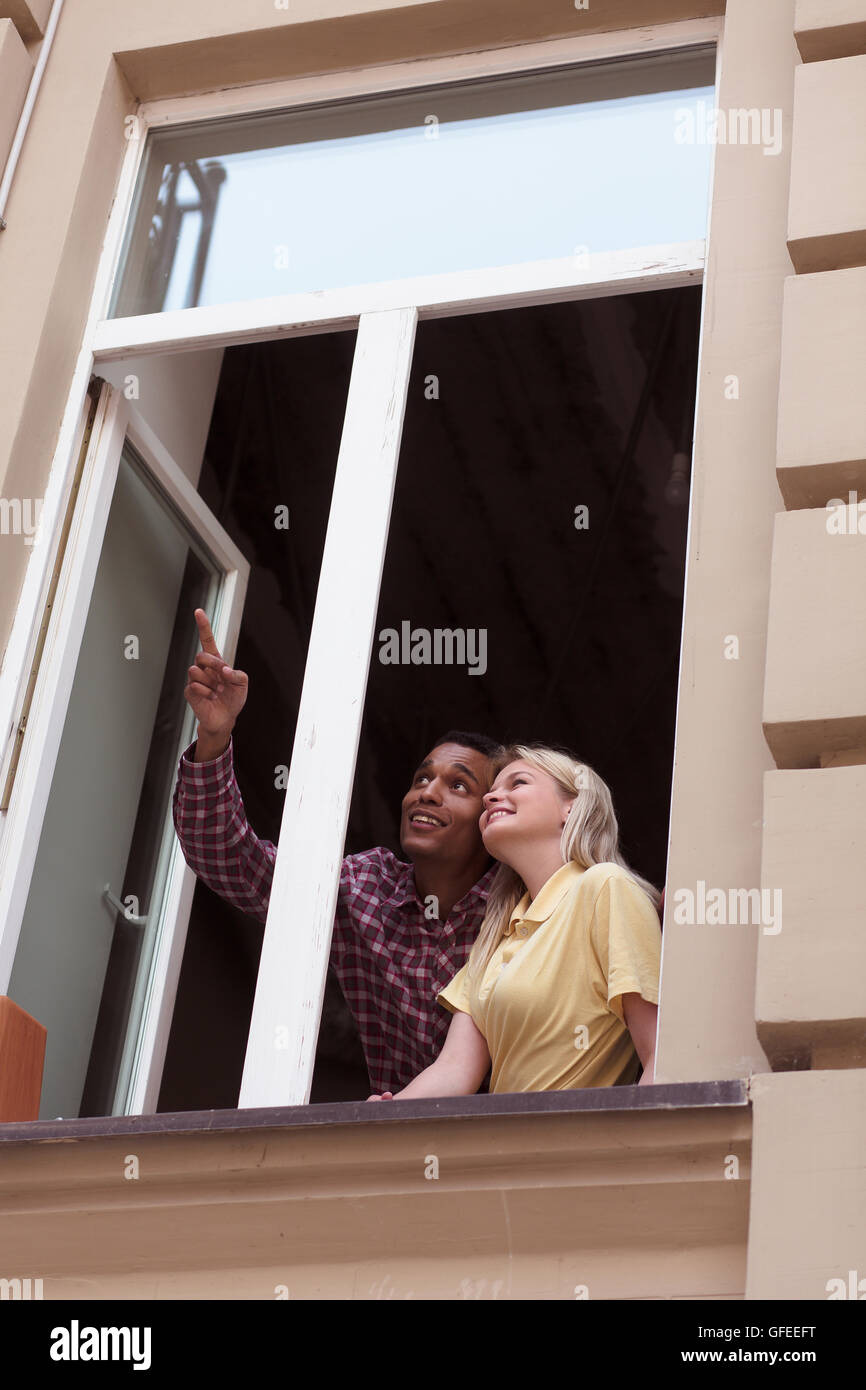 Happy couple looking from window Stock Photo - Alamy