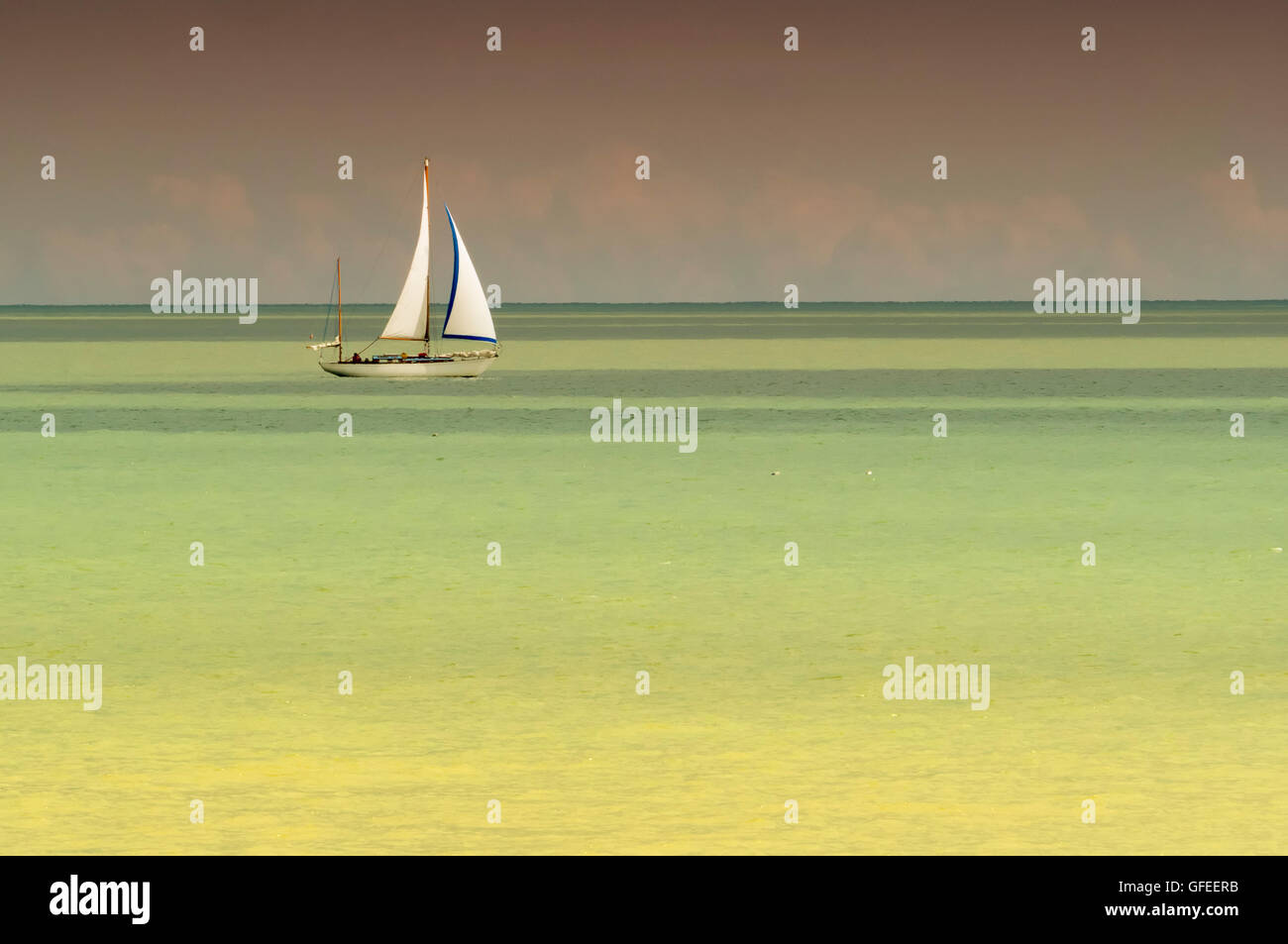 A sloop under sail on golden seas under a rose-tinged sky Stock Photo ...