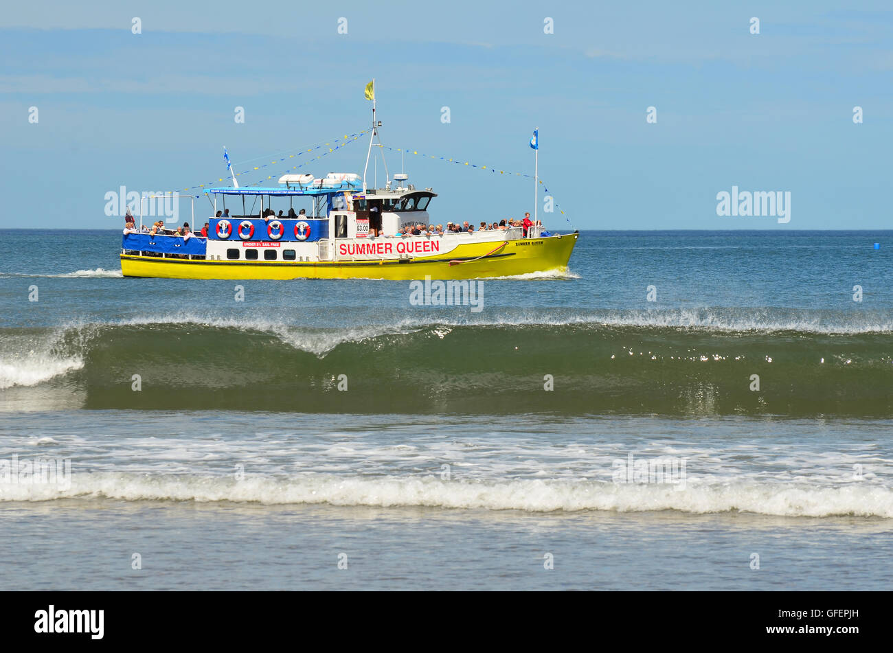 View from Whitby beach of a pleasure boat sailing in to Whitby Harbour ...
