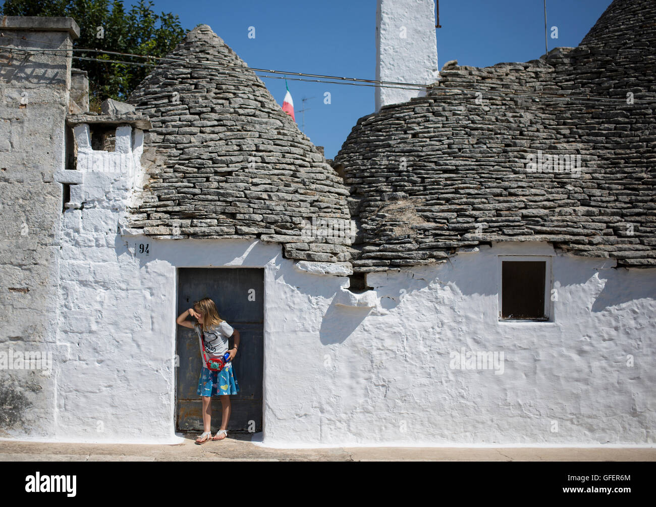 A young girl waits in a doorway of a Trulli in Alberobello, Puglia ...
