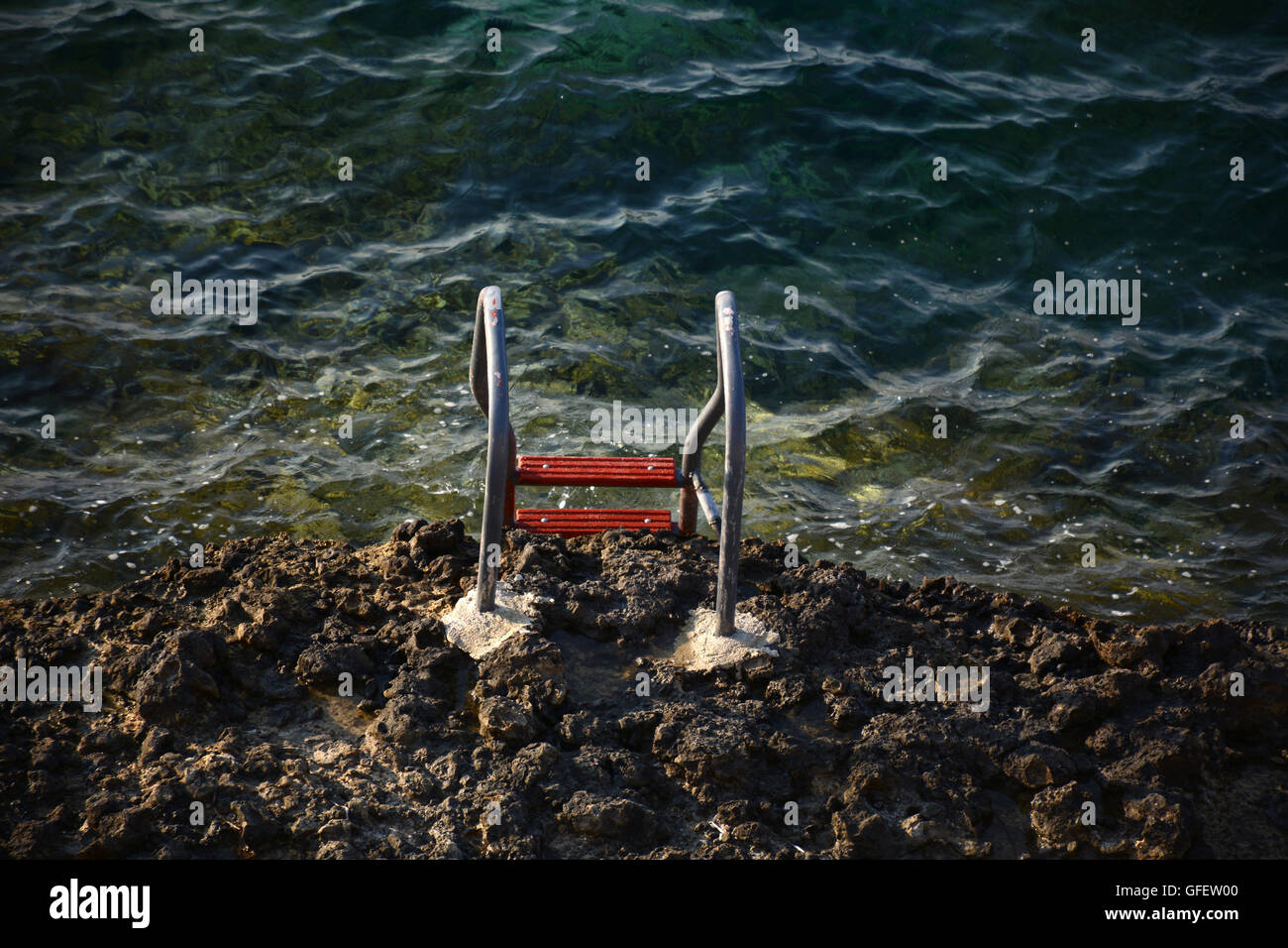 Sea ladder for swimmers next to the rocky shores of the crystal clear ...