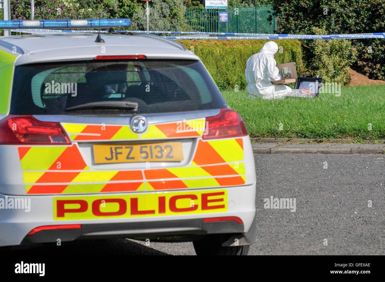 A forensics Scene of Crime Officer SOCO examines a crime scene while a ...