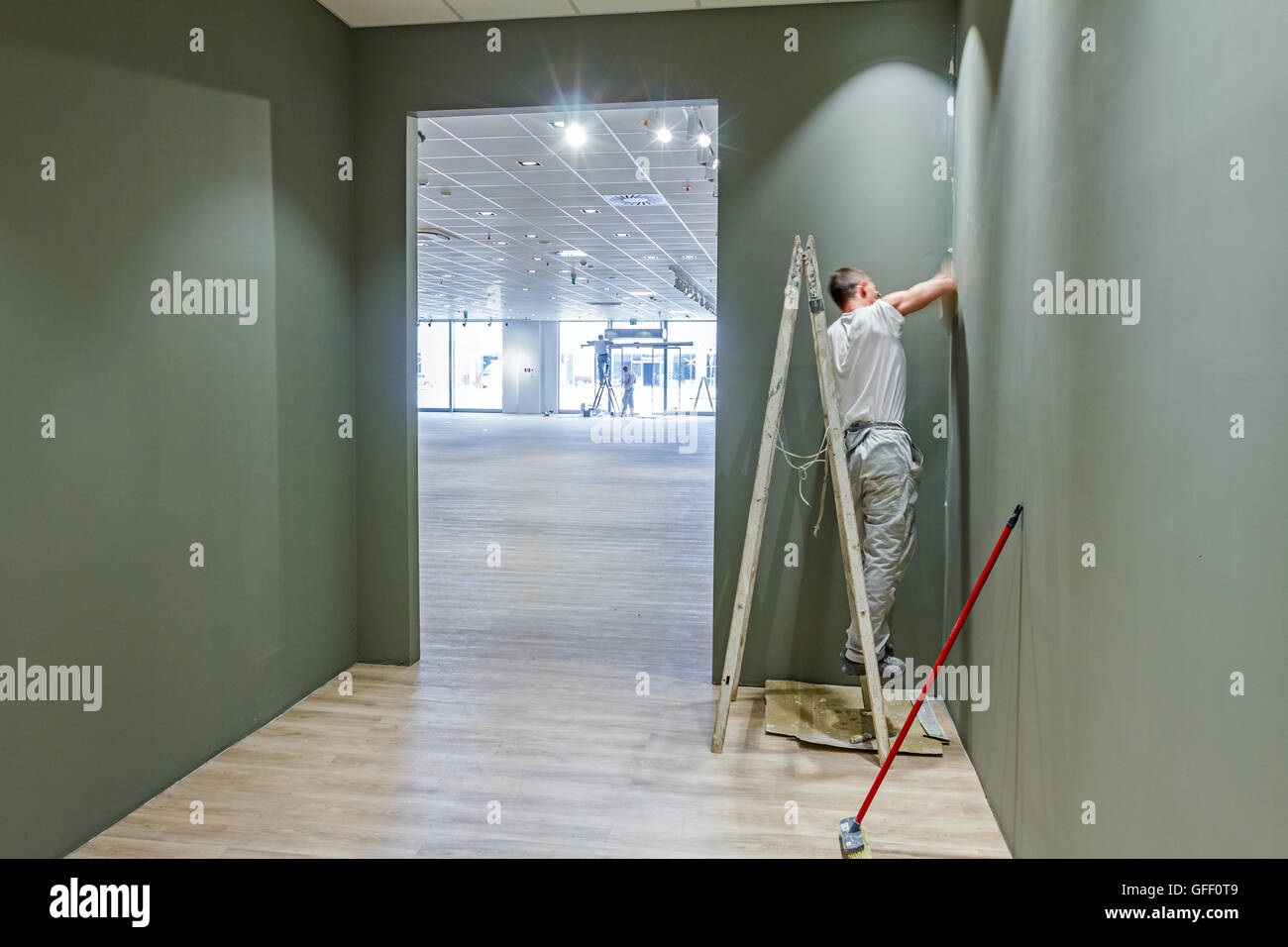 Workers are used wooden ladder to complete modern office ceiling with ...