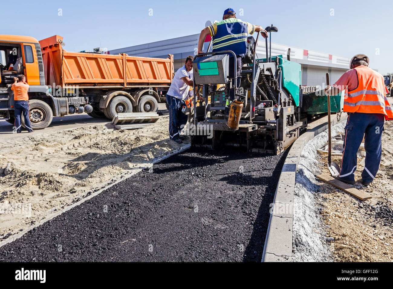 Hot asphalt is applied to the ground by construction crew with tarmac ...