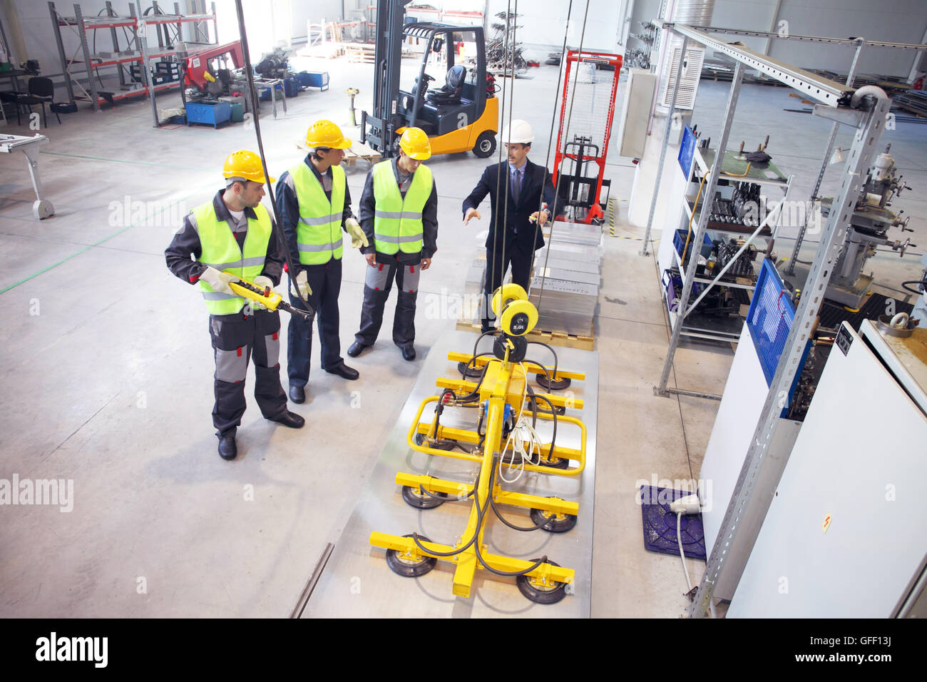 Manager and workers near metal sheet lifting device at factory Stock ...