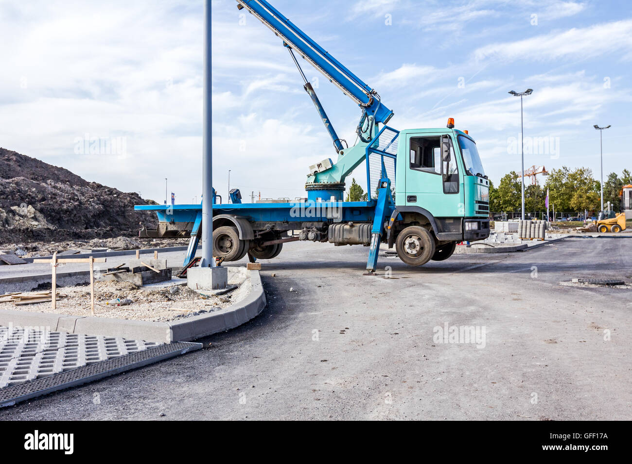 Truck with elevated bucket has lateral stabilizer extended to make ...