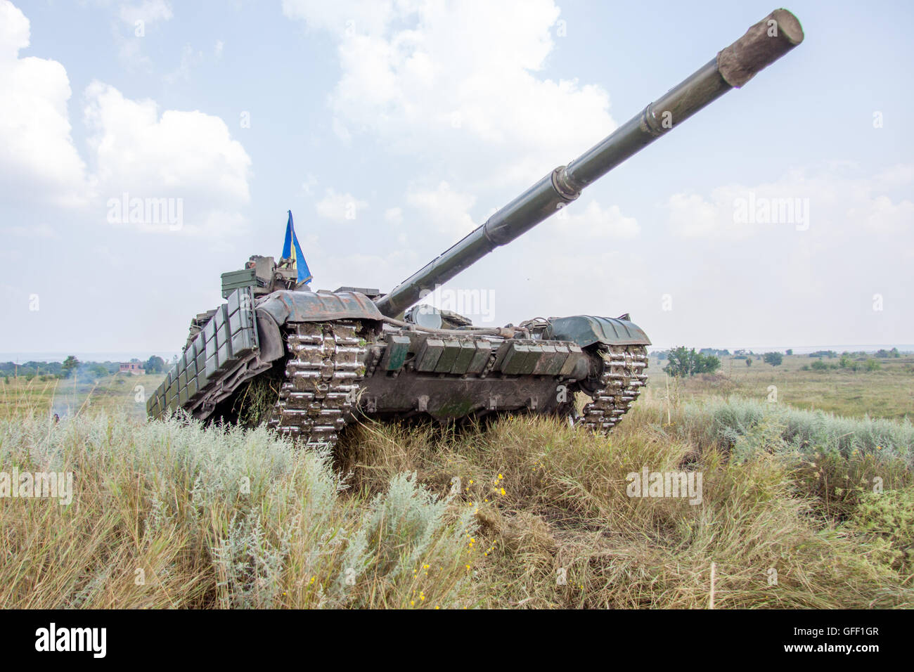 Main battle tank under the Ukrainian flag at a firing range in summer ...