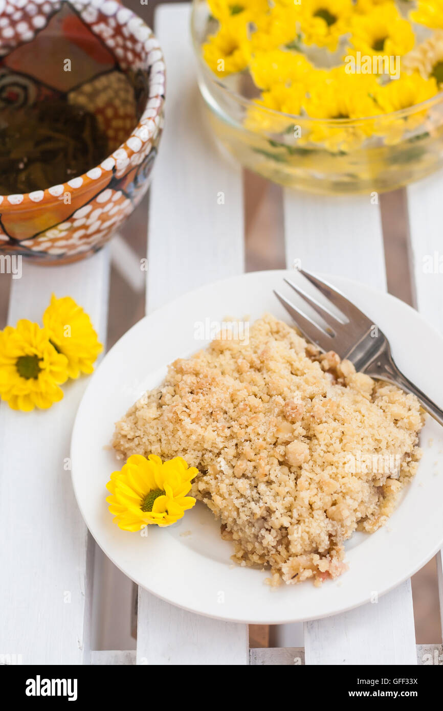 piece of cake with crumbs, tea and yellow flowers on white wooden ...