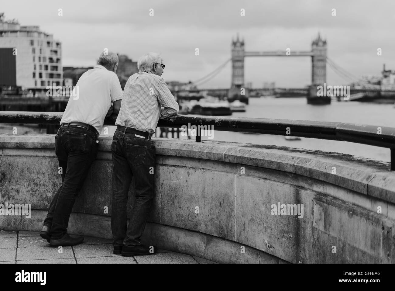 Two men chat over old times over looking tower bridge Stock Photo - Alamy