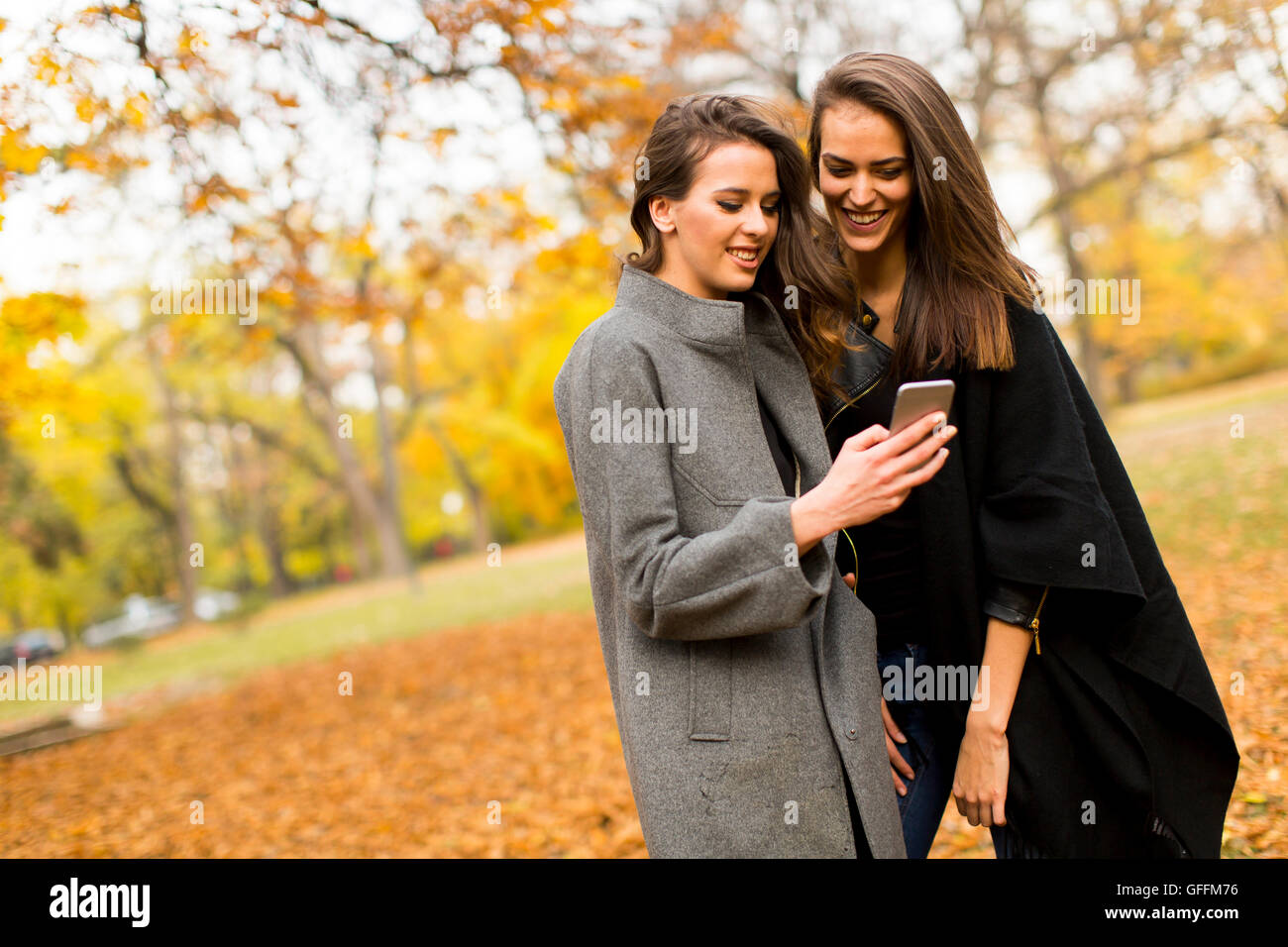 Young women with mobile phone in the autumn park Stock Photo - Alamy