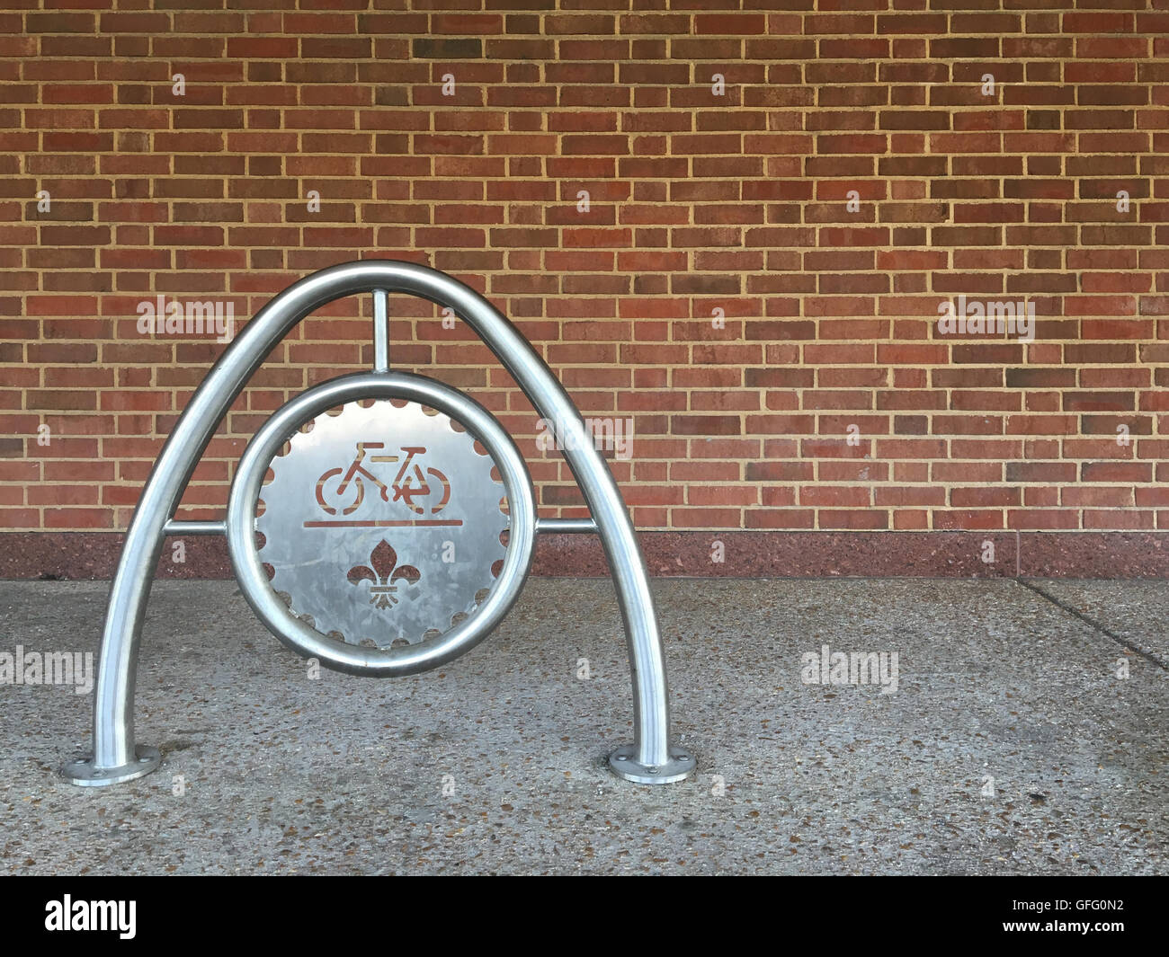 Stainless steel bike rack on a sidewalk by a red brick wall Stock Photo ...