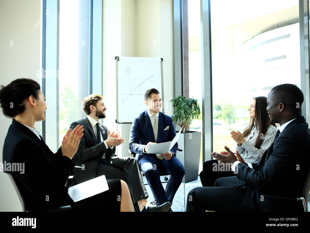 Group of five young people discussing something while sitting at the ...