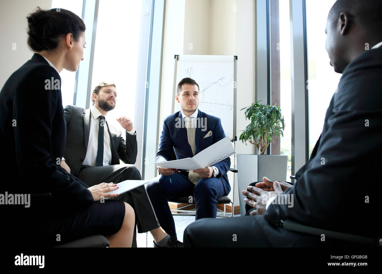 Group of five young people discussing something while sitting at the ...