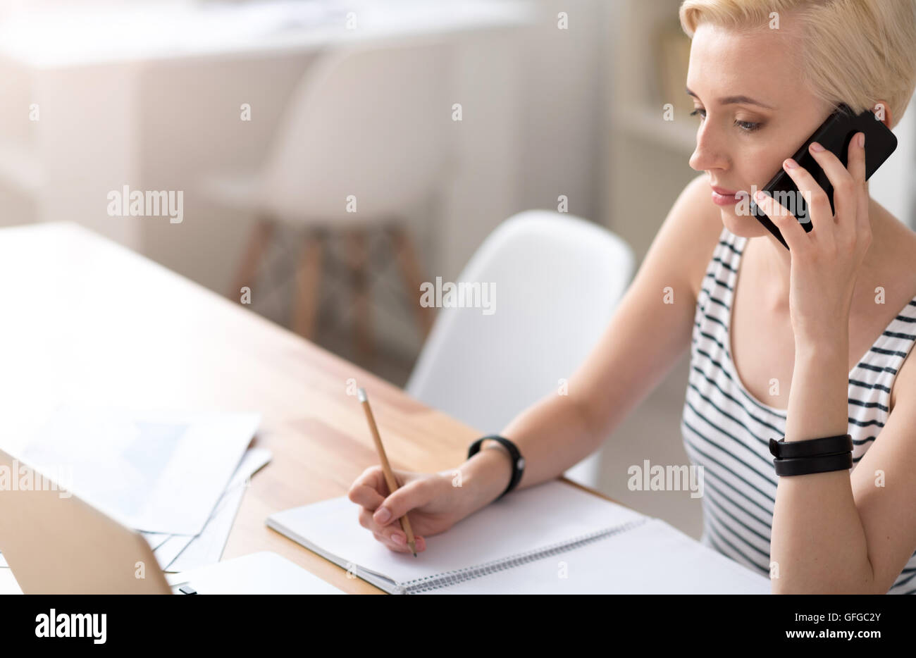 Woman taking notes and talking on smartphone Stock Photo - Alamy