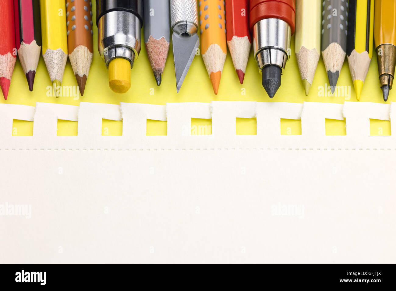 yellow writing desk background with paper and colorful pencils, macro ...