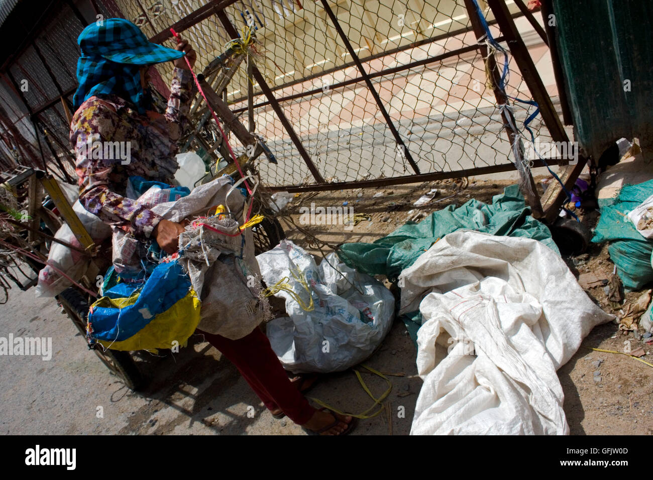 A scavenger woman is sorting sacks used for collecting recyclable ...