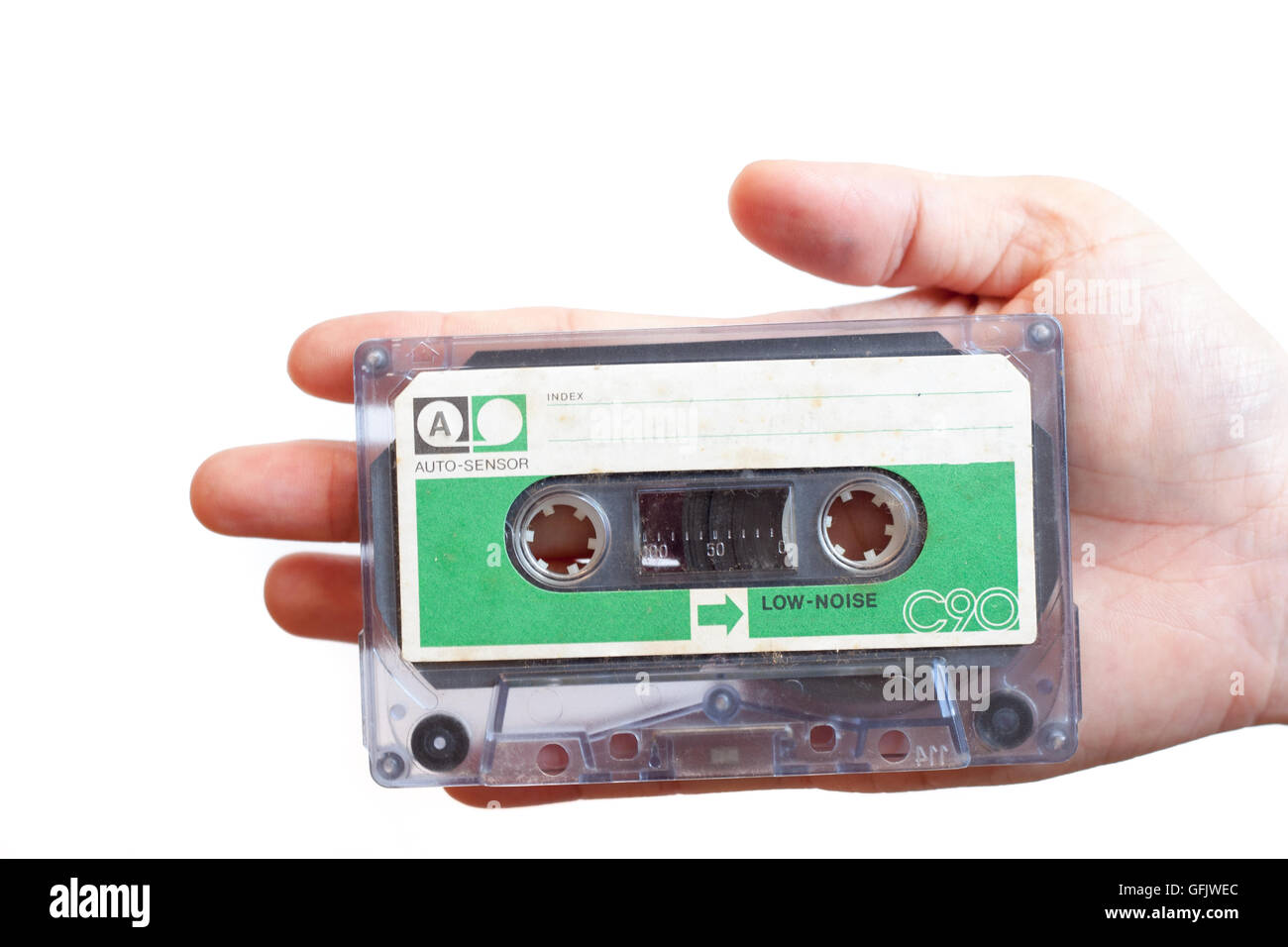 Holding Retro green label compact cassette by hand on white isolated ...