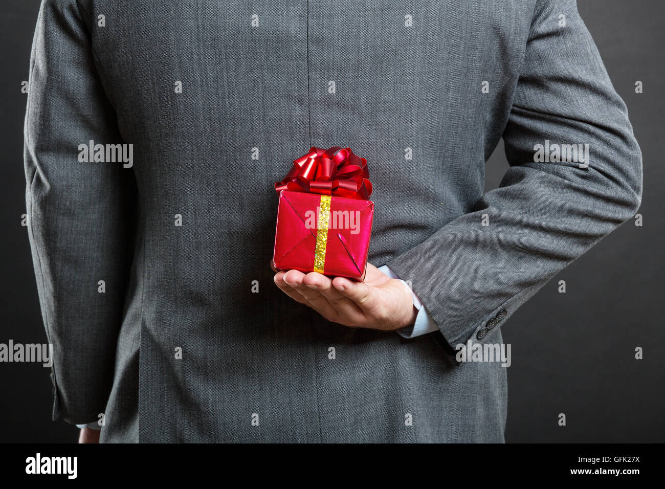 Man with a gift behind his back Stock Photo - Alamy