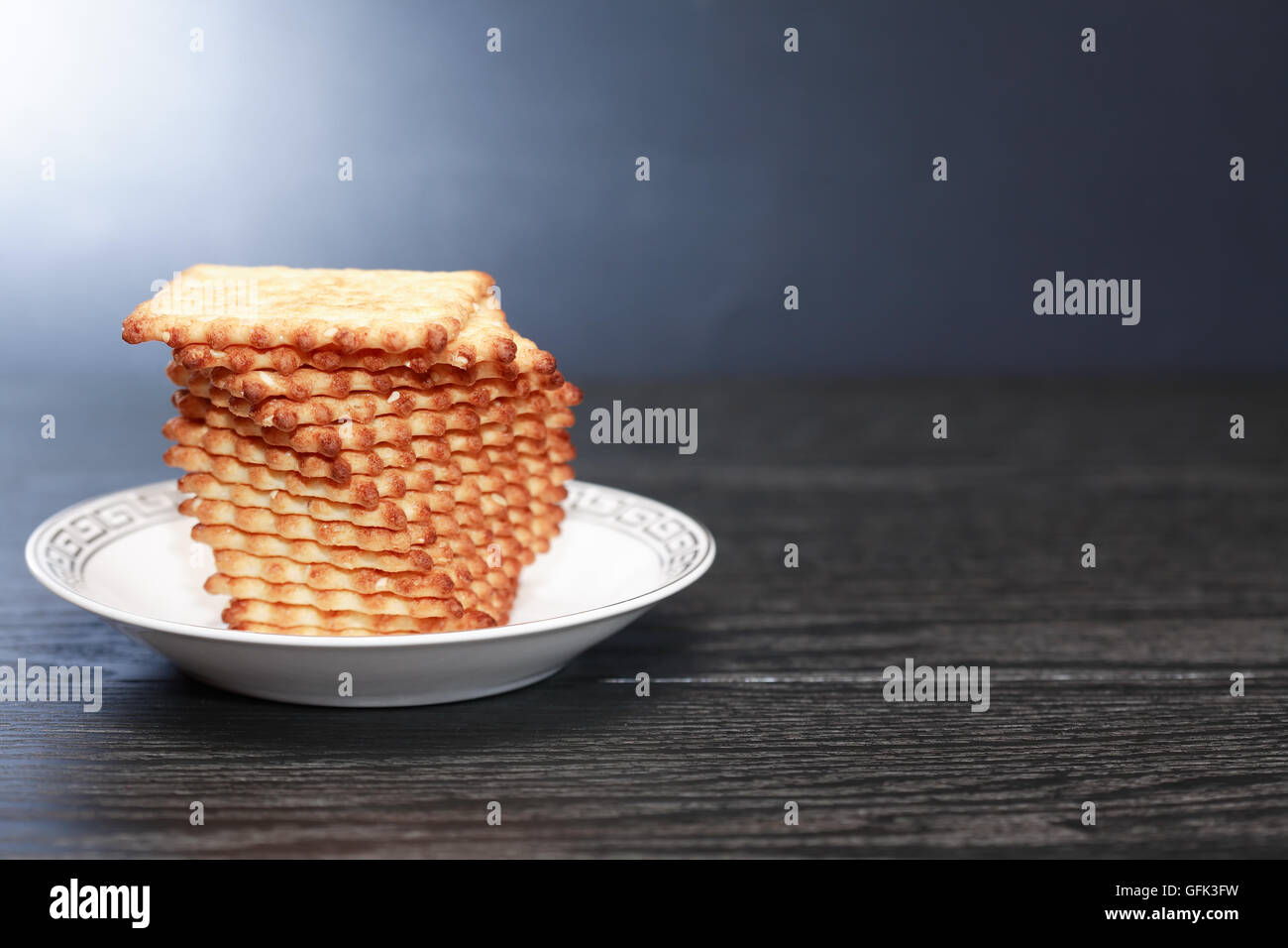 Stack of crackers on saucer against dark background Stock Photo - Alamy