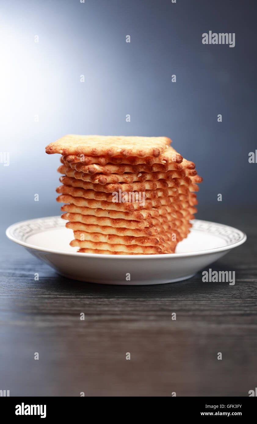 Stack of crackers on saucer against dark background Stock Photo - Alamy