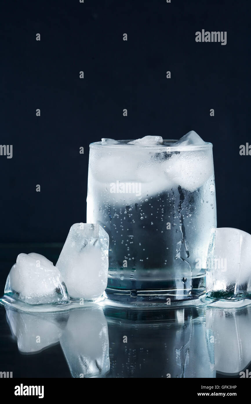 Glass of mineral water near ice cubes on dark background Stock Photo - Alamy