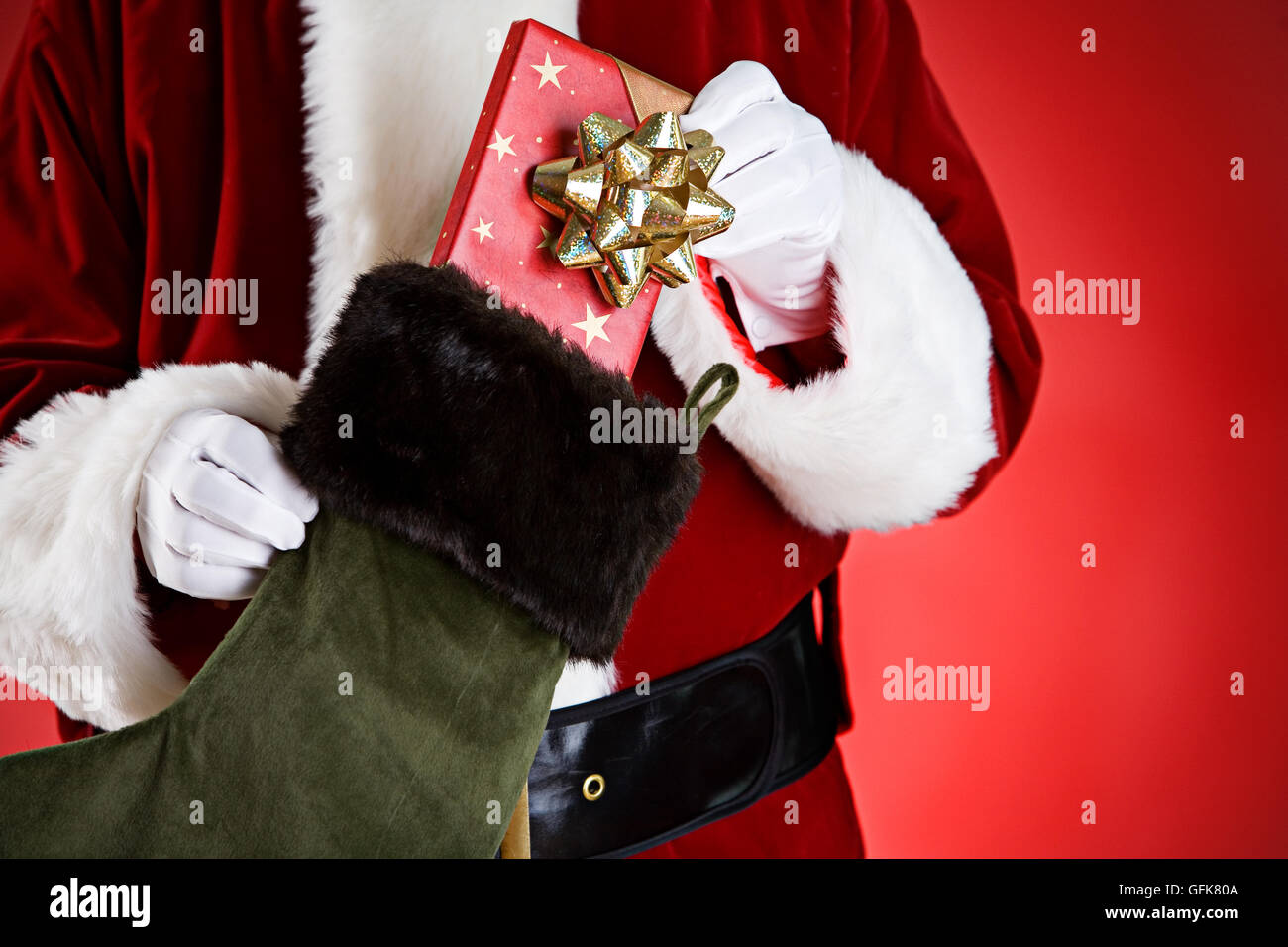 Anonymous Santa Claus on a red background holding various props, gifts ...