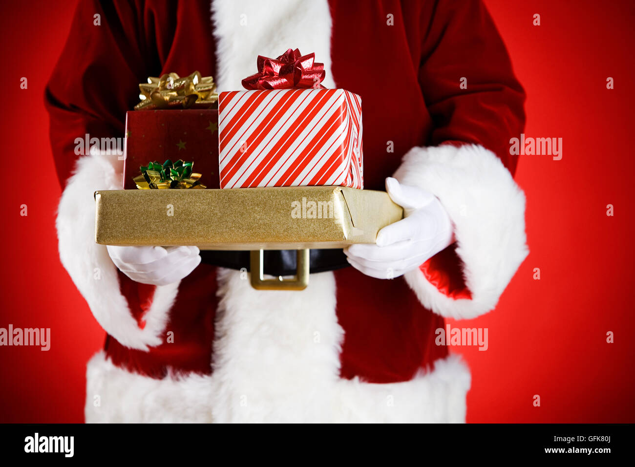Anonymous Santa Claus on a red background holding various props, gifts ...