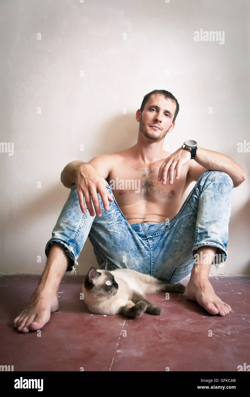 Young man is sitting on the floor with his cat Stock Photo - Alamy