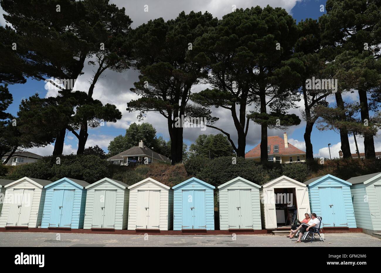 People sit outside beach huts on Avon Beach in Mudeford, Dorset Stock ...