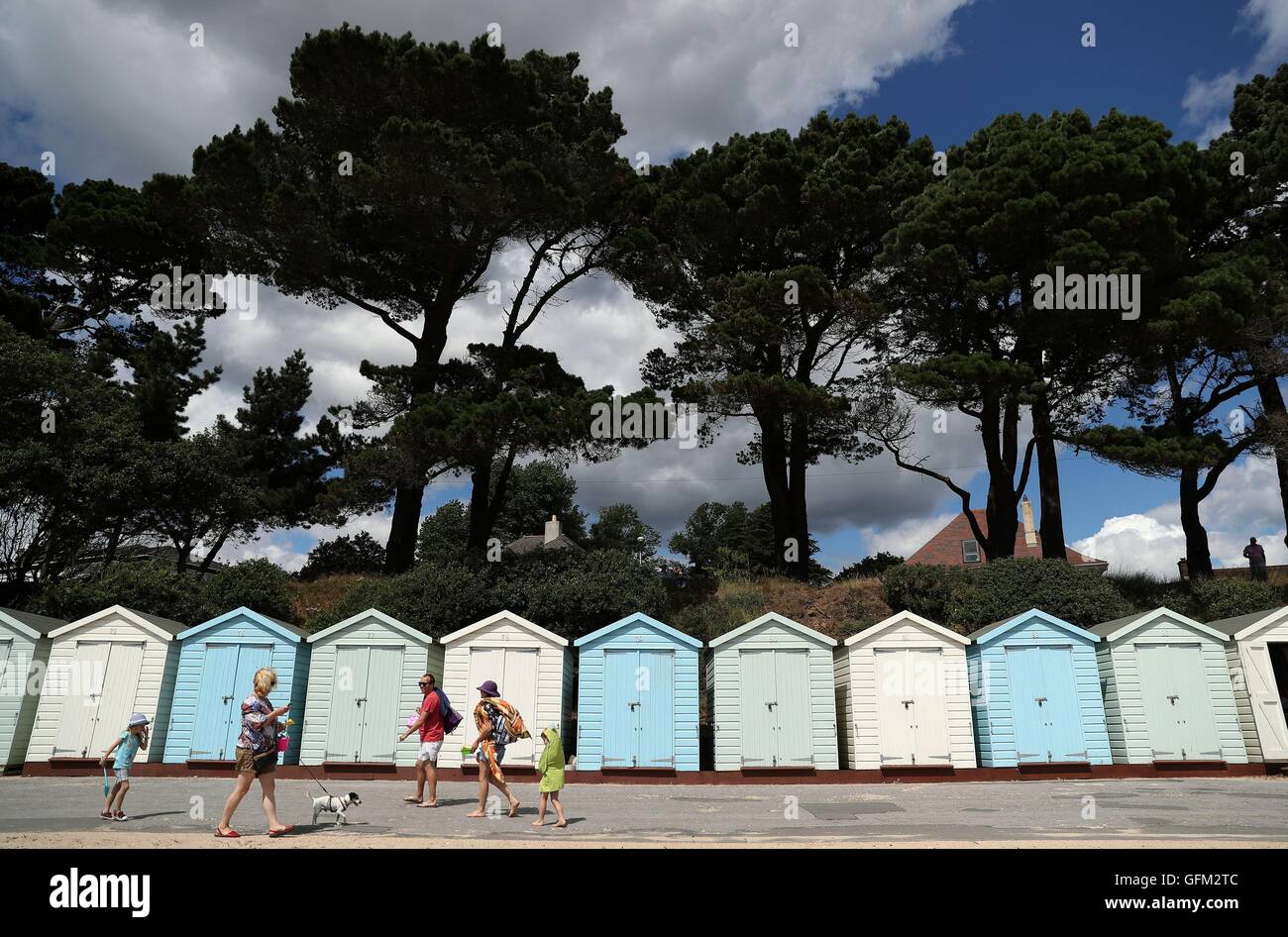 People walk past beach huts on Avon Beach in Mudeford, Dorset Stock ...