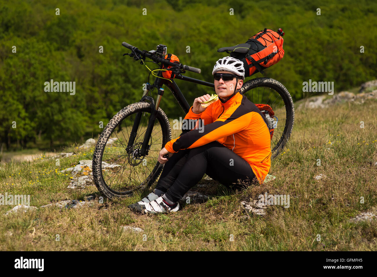 Active man sitting on bike and eating sandwich Stock Photo - Alamy
